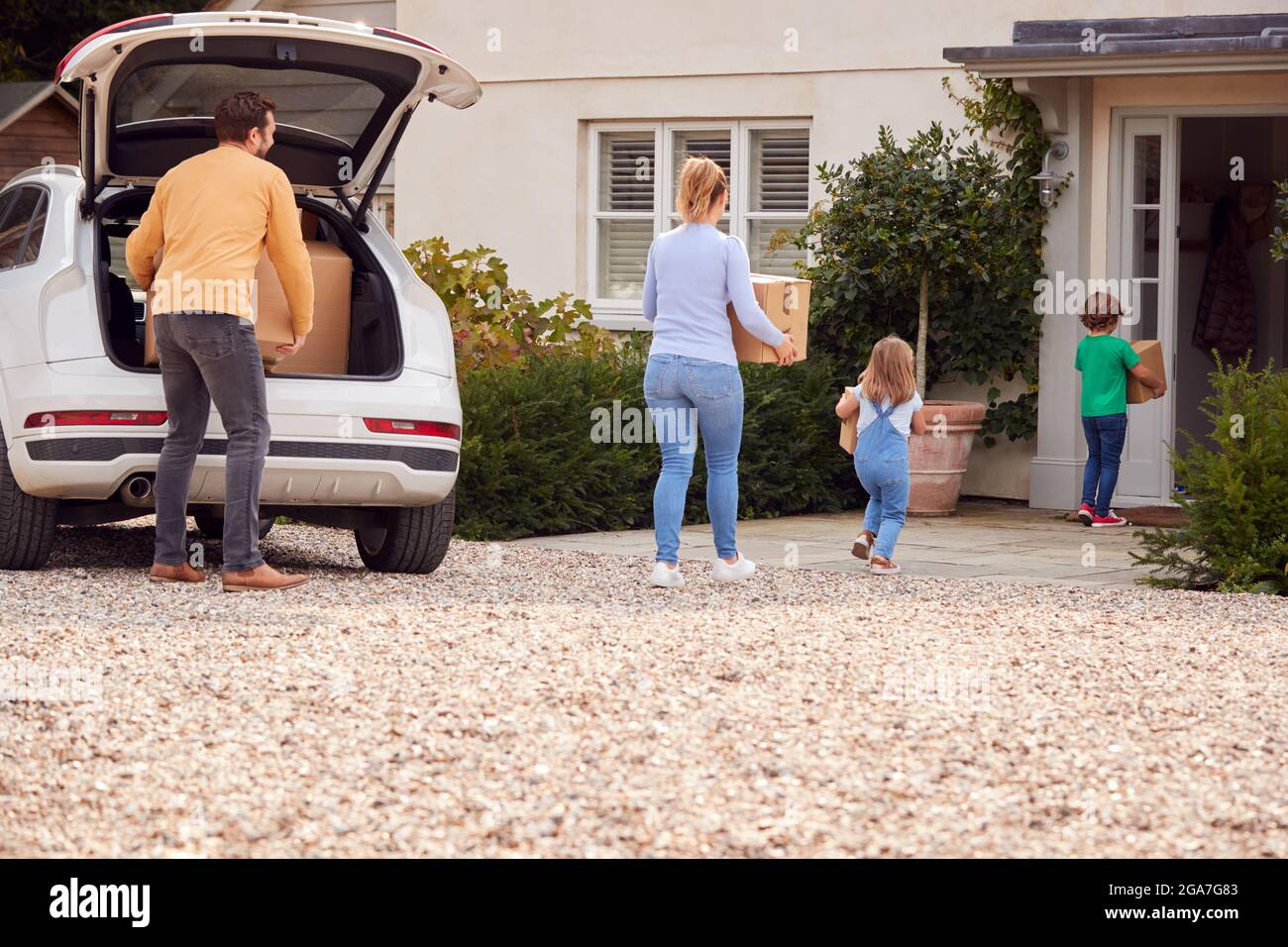 Family Outside New Home On Moving Day Loading Or Unloading Boxes From ...