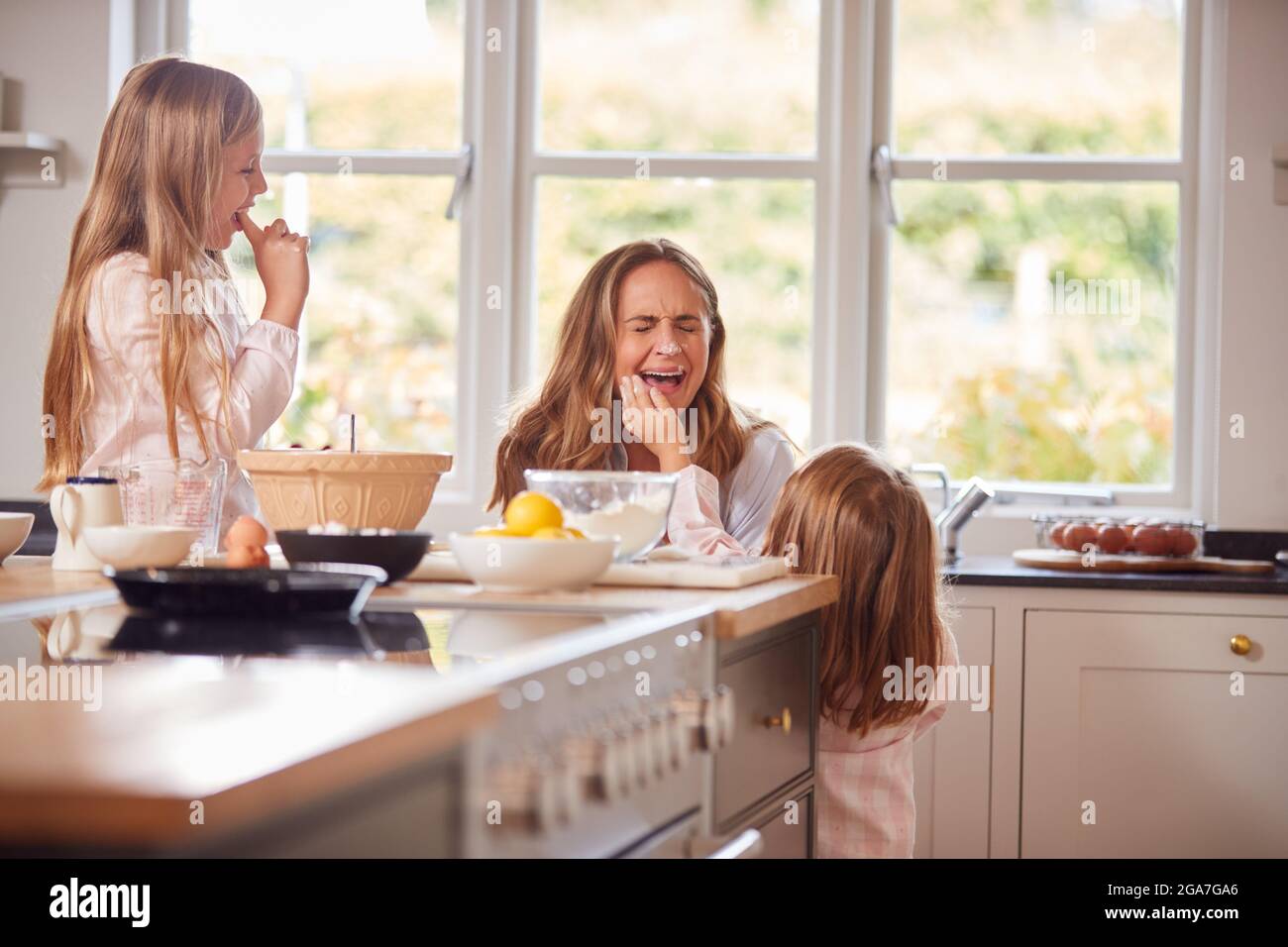 Mother And Two Daughters Making Messy Pancakes In Kitchen At Home ...