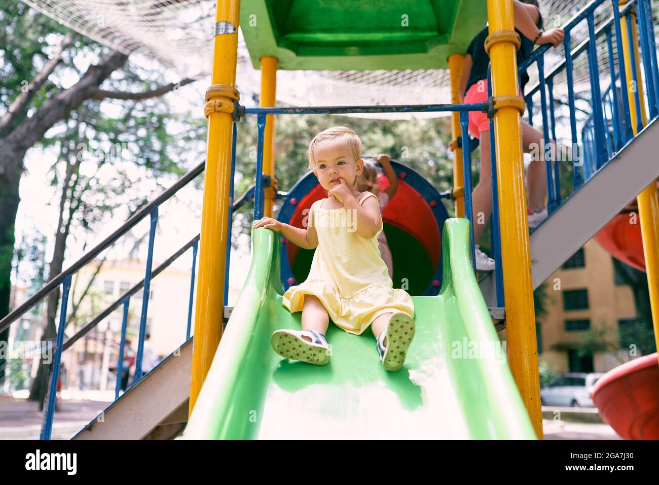 Little girl in a dress sits on a slide Stock Photo - Alamy