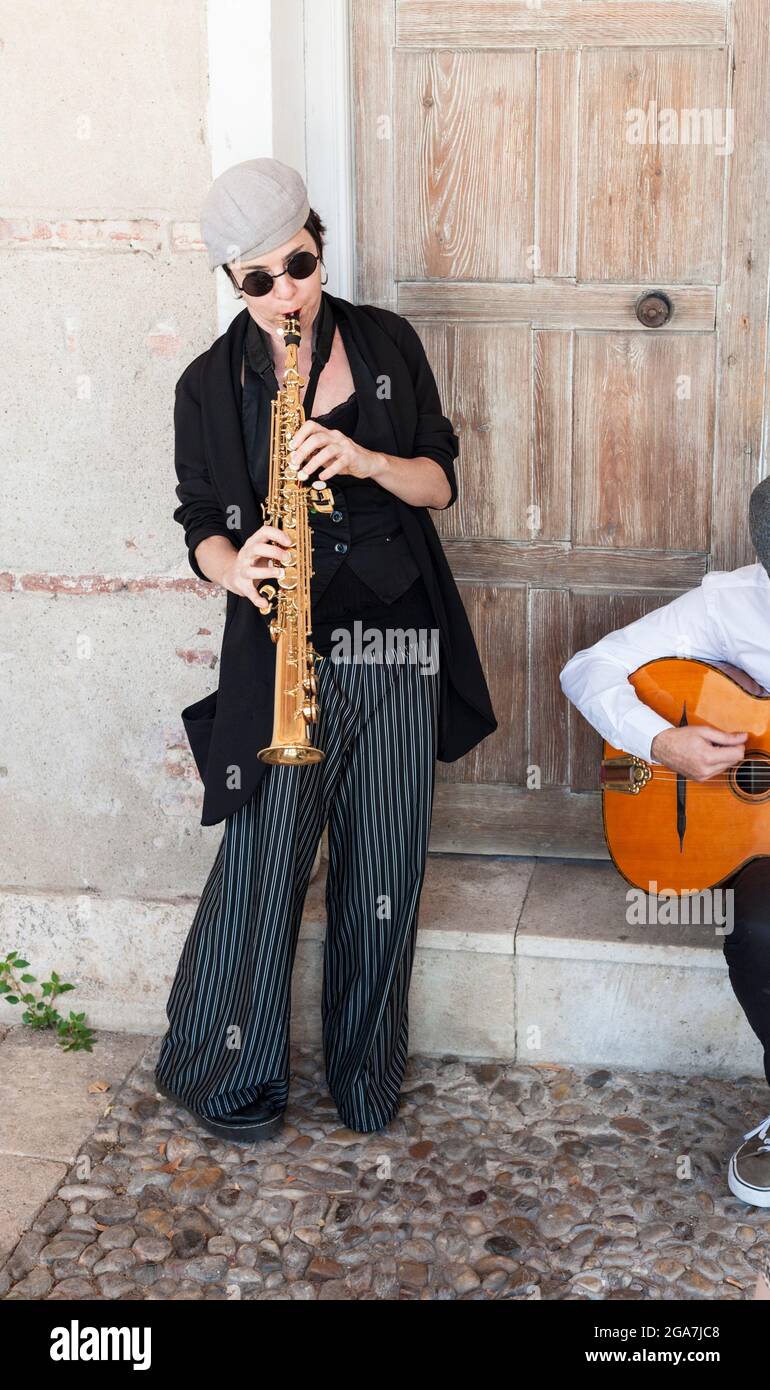Jazz musicians dressed in retro style playing in the street. A brunette ...