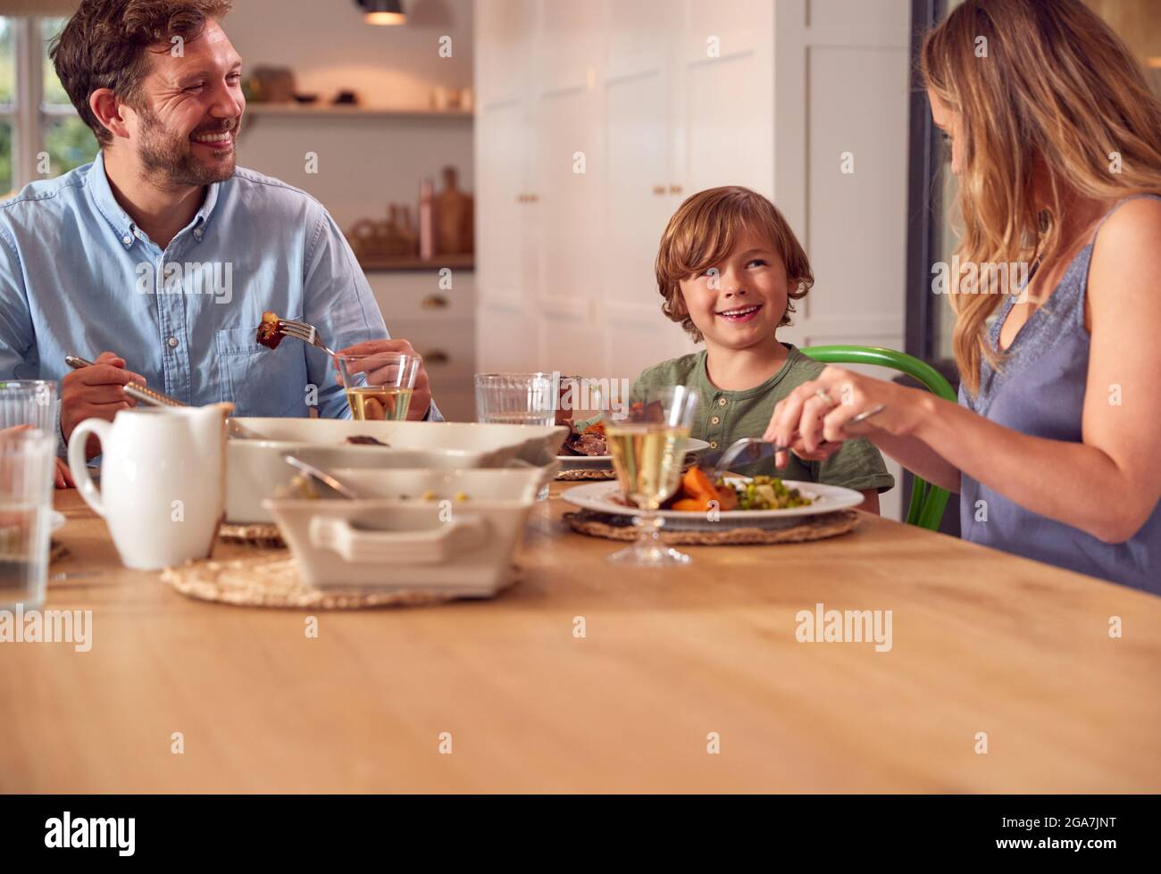 Family Sitting Around Table At Home Enjoying Meal Together Stock Photo ...