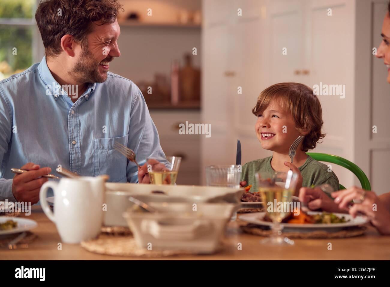 Family Sitting Around Table At Home Enjoying Meal Together Stock Photo ...