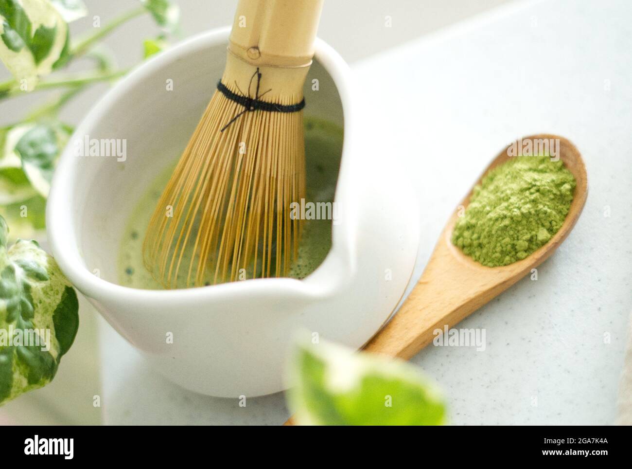Mixing green Japanese matcha powder in a white ceramic chawan with ...
