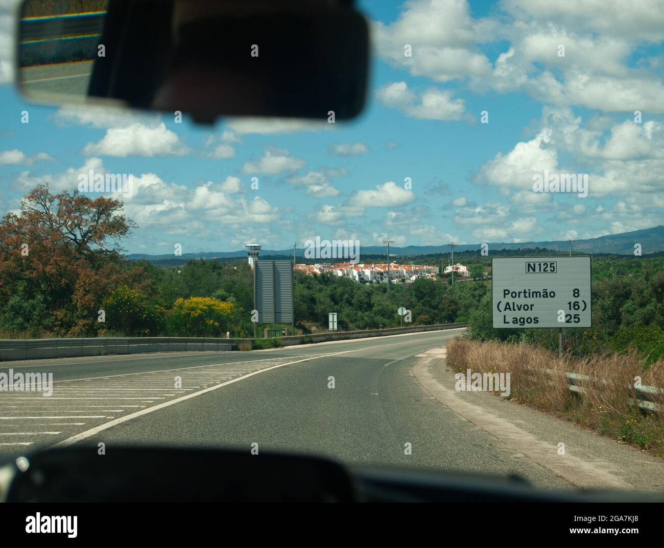 A view on the road from inside the car, cloudy sky and the road signs ...