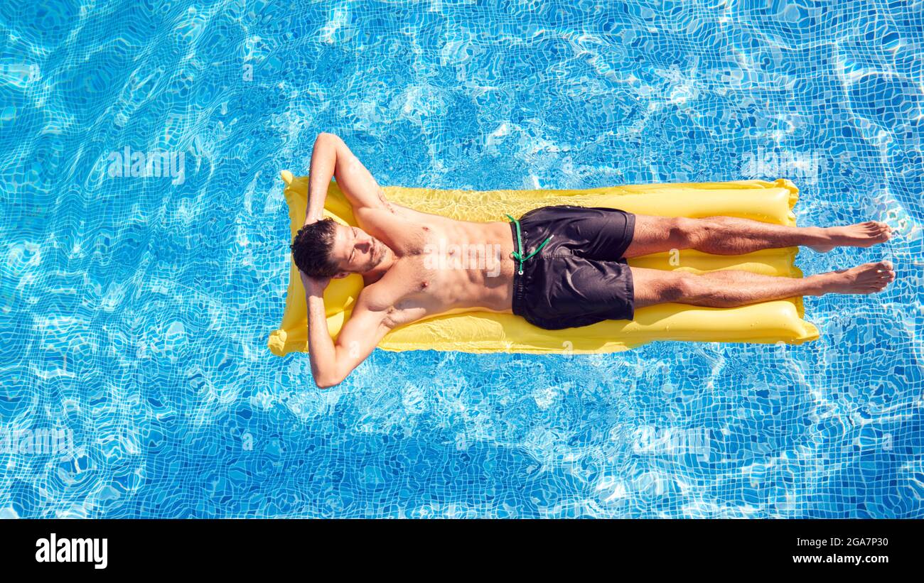 Overhead Shot Of Man In Swim Shorts Floating On Air Bed On Summer ...