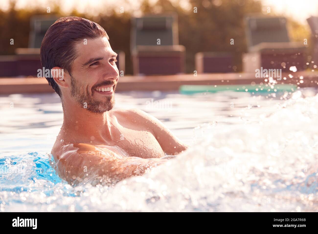 Smiling Man Splashing Water On Summer Vacation In Outdoor Swimming Pool ...