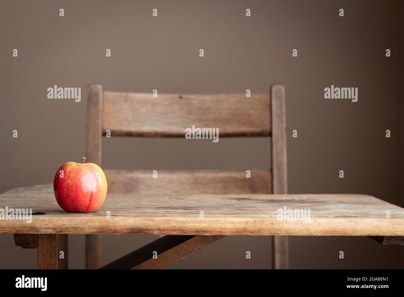 single red apple sitting on vintage wood desk with neutral background ...