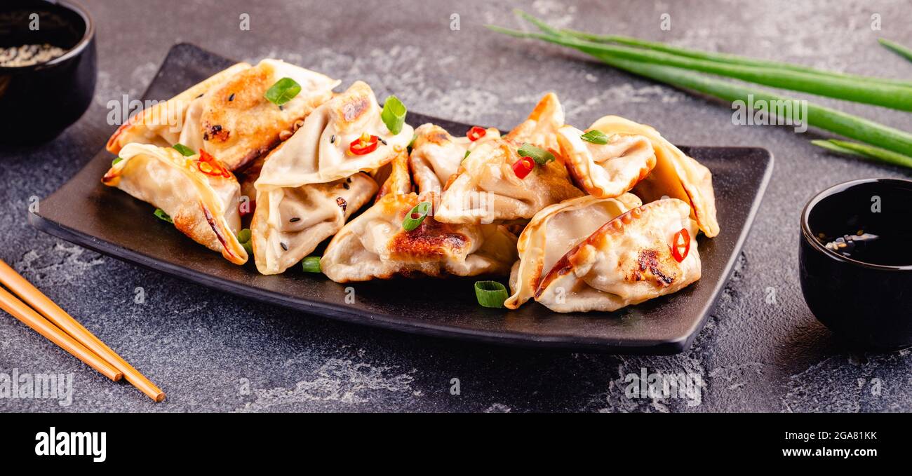 Fried dumplings served with green onions, sesame seeds and chili ...