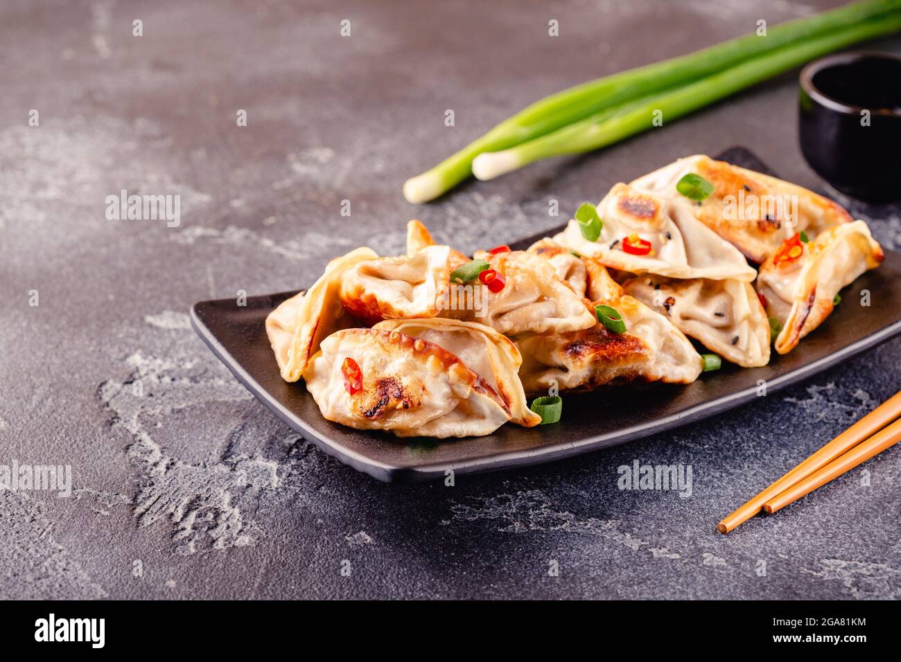 Fried dumplings served with green onions, sesame seeds and chili ...
