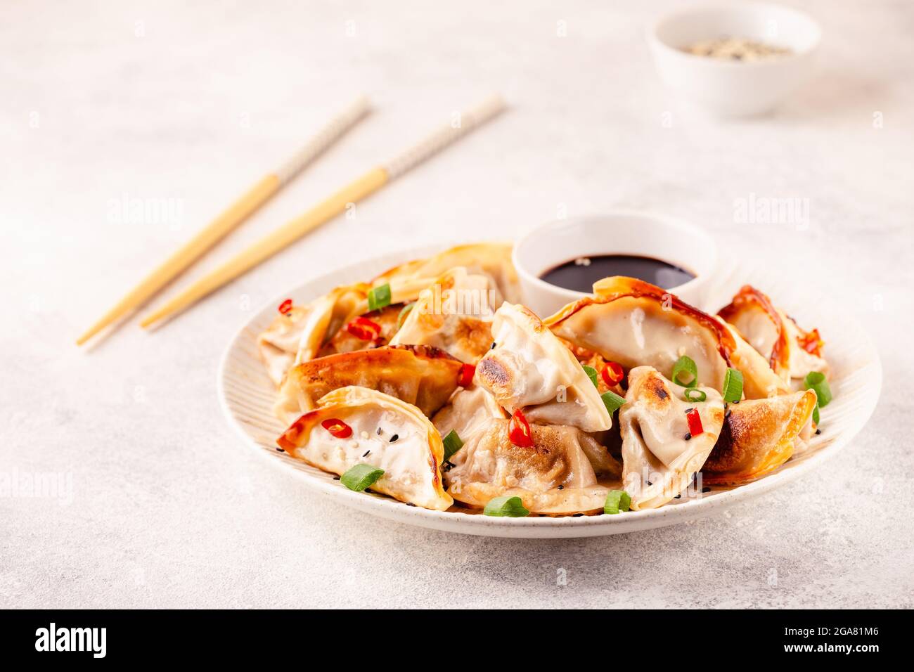 Fried dumplings served with green onions, sesame seeds and chili ...