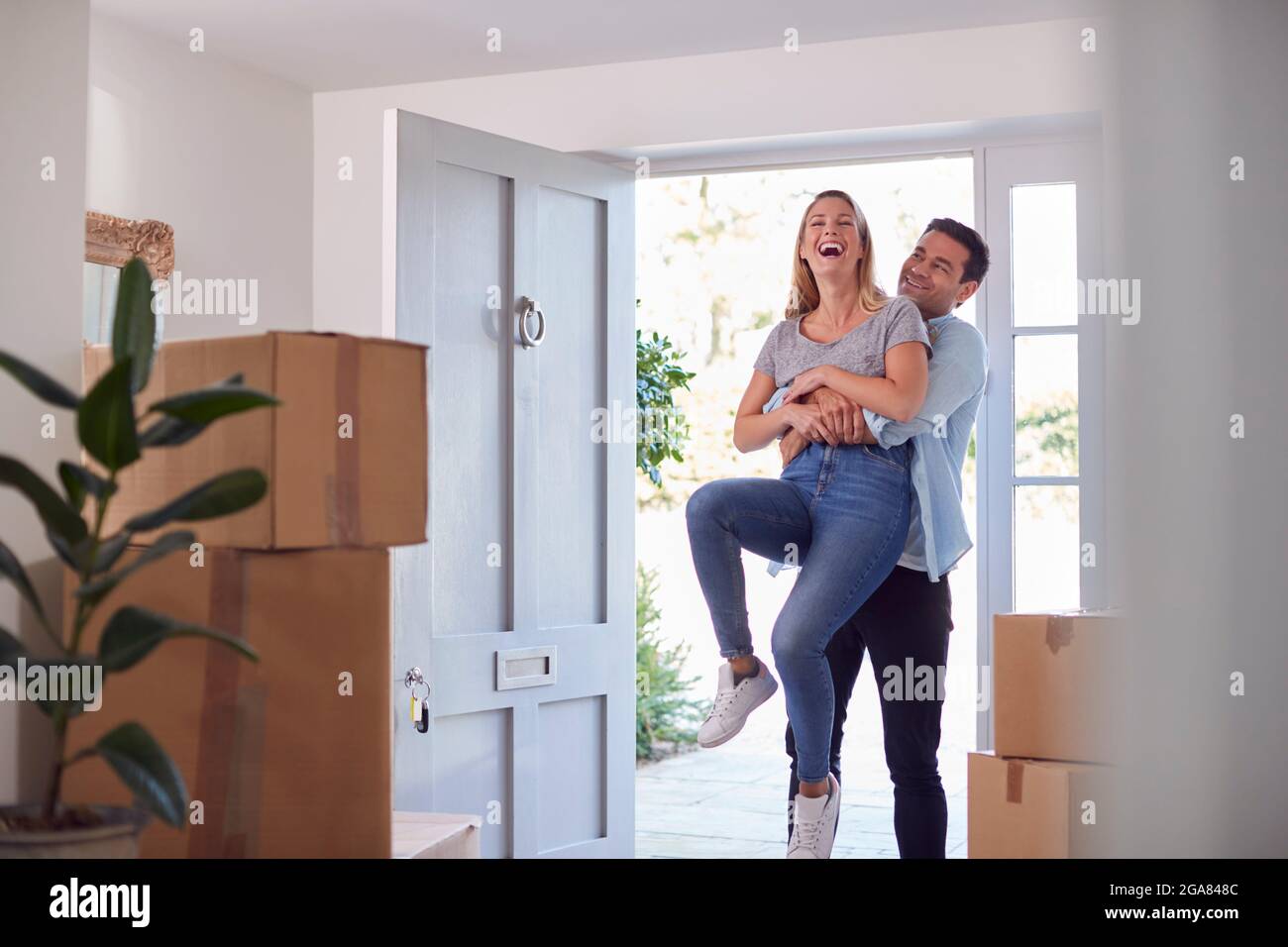 Man Carrying Woman Over Threshold Of New Home As Couple Move In ...