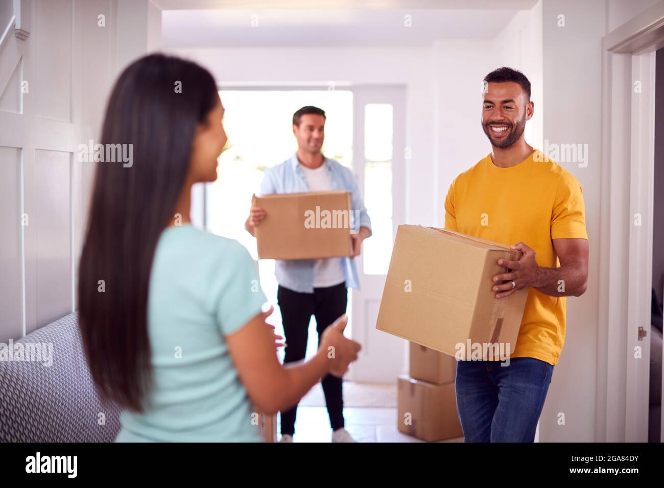 Friend Helping Couple Carry Boxes Through Front Door Of New Home On ...