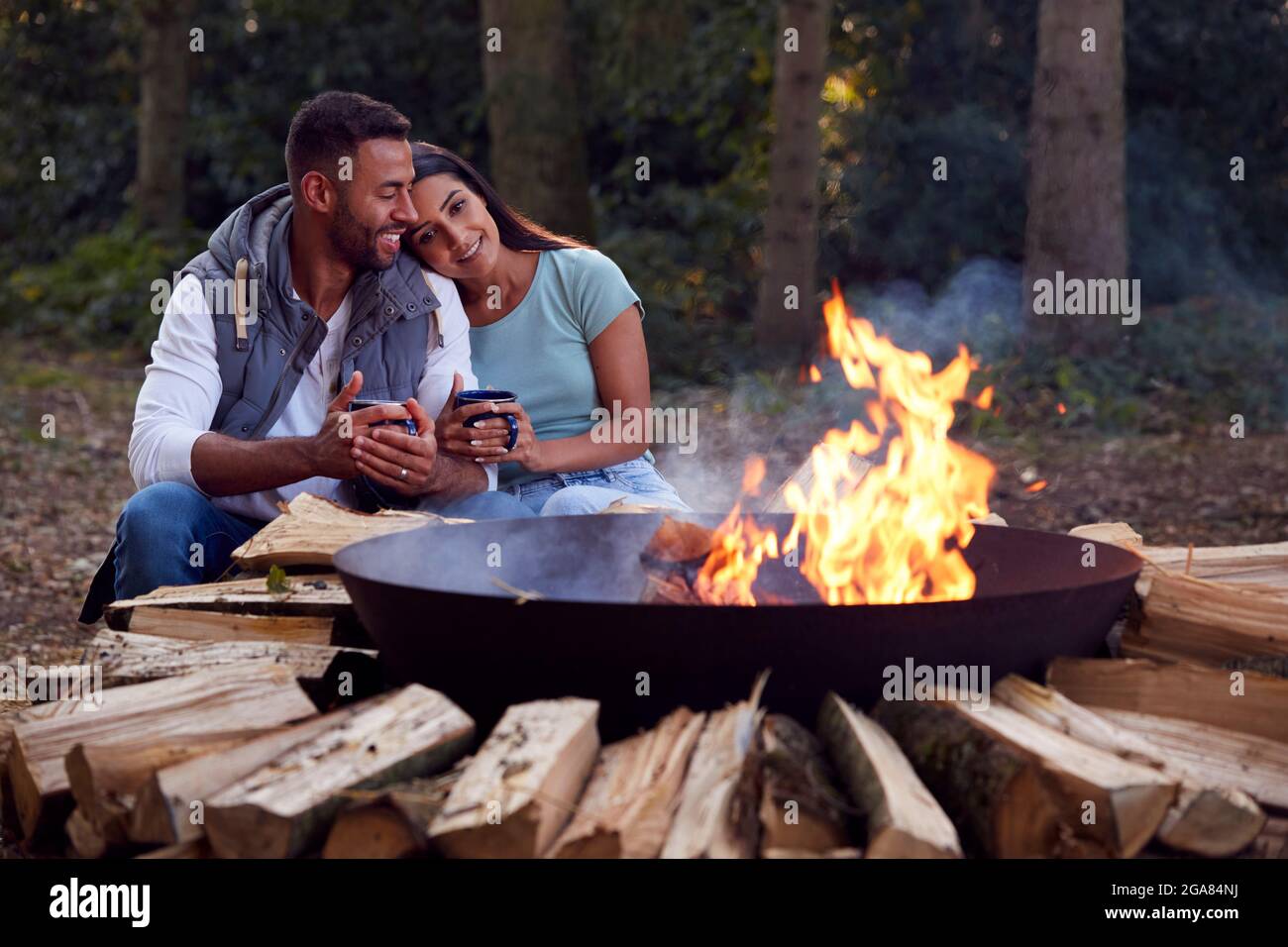 Romantic Couple Camping Sitting By Bonfire In Fire Bowl With Hot Drinks ...