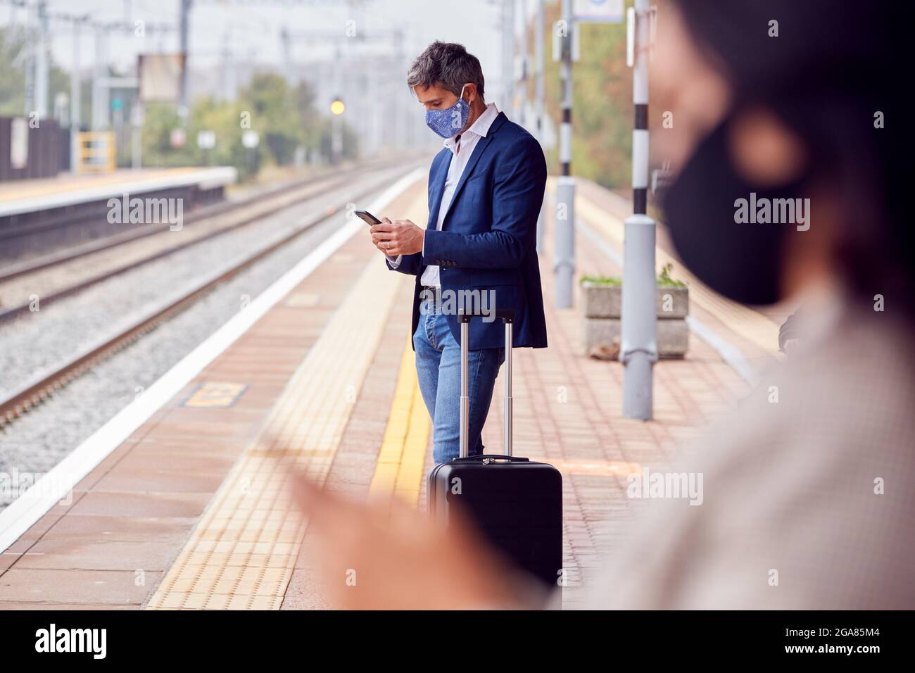Business Commuters On Railway Platform With Mobile Phones Wearing PPE ...