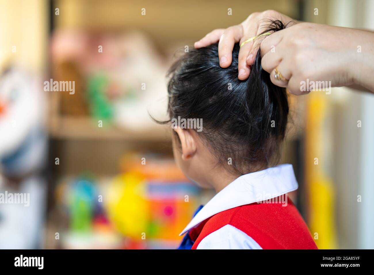 Female hand fixing the hair of a little girl against a blurred ...
