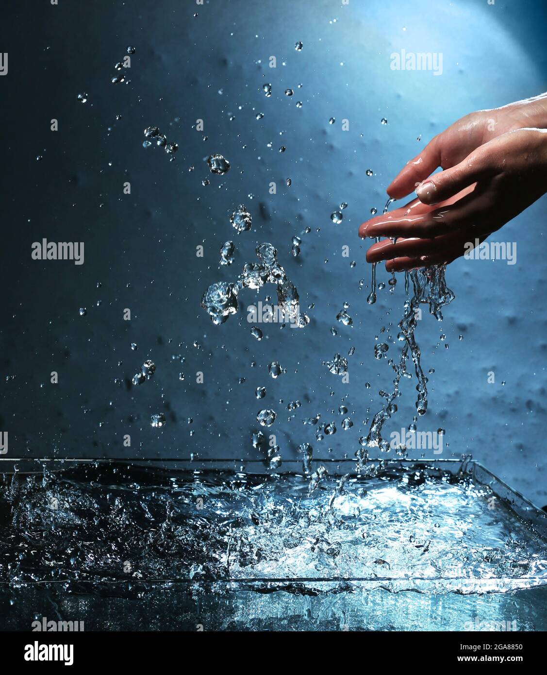 Female hands with water splashing on blue background Stock Photo - Alamy