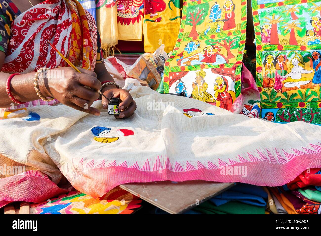 Young Bengali female artist painting Pattachitra or Patachitra on white ...