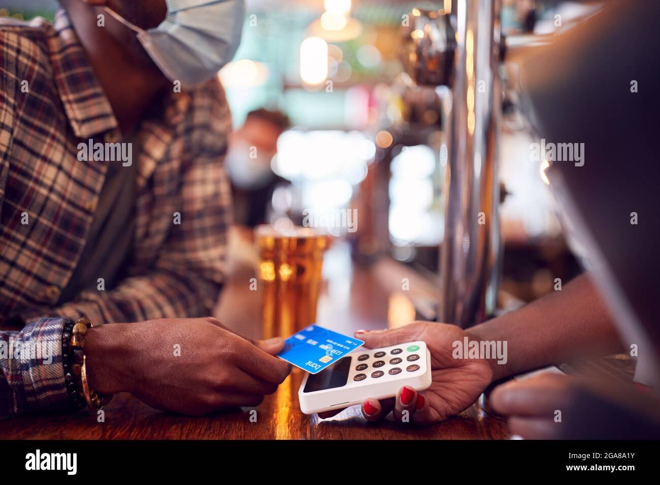 Male Customer Wearing Mask In Bar Making Contactless Payment For Drinks ...