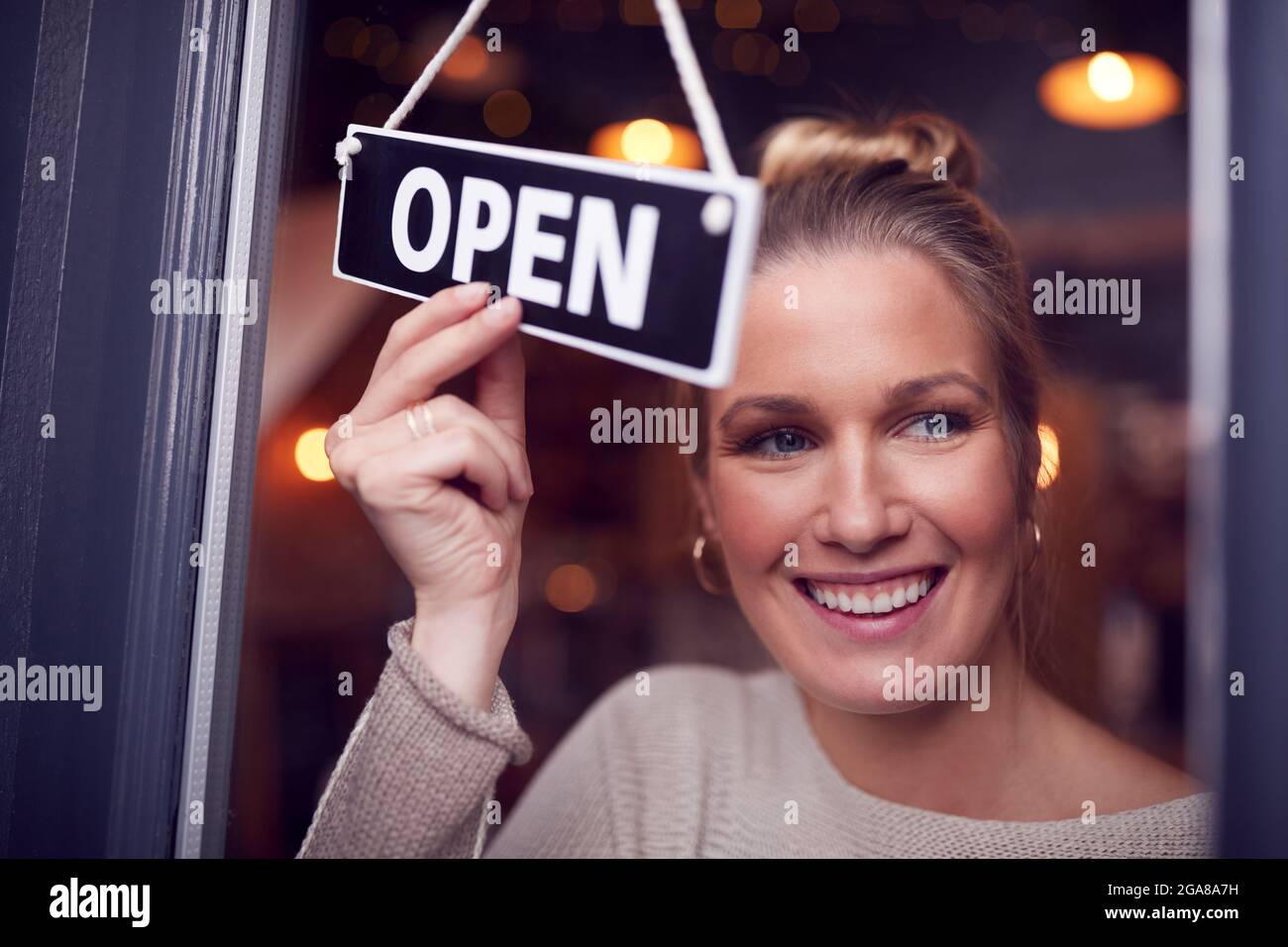 Female Owner Of Small Business Turning Round Open Sign On Shop Door ...