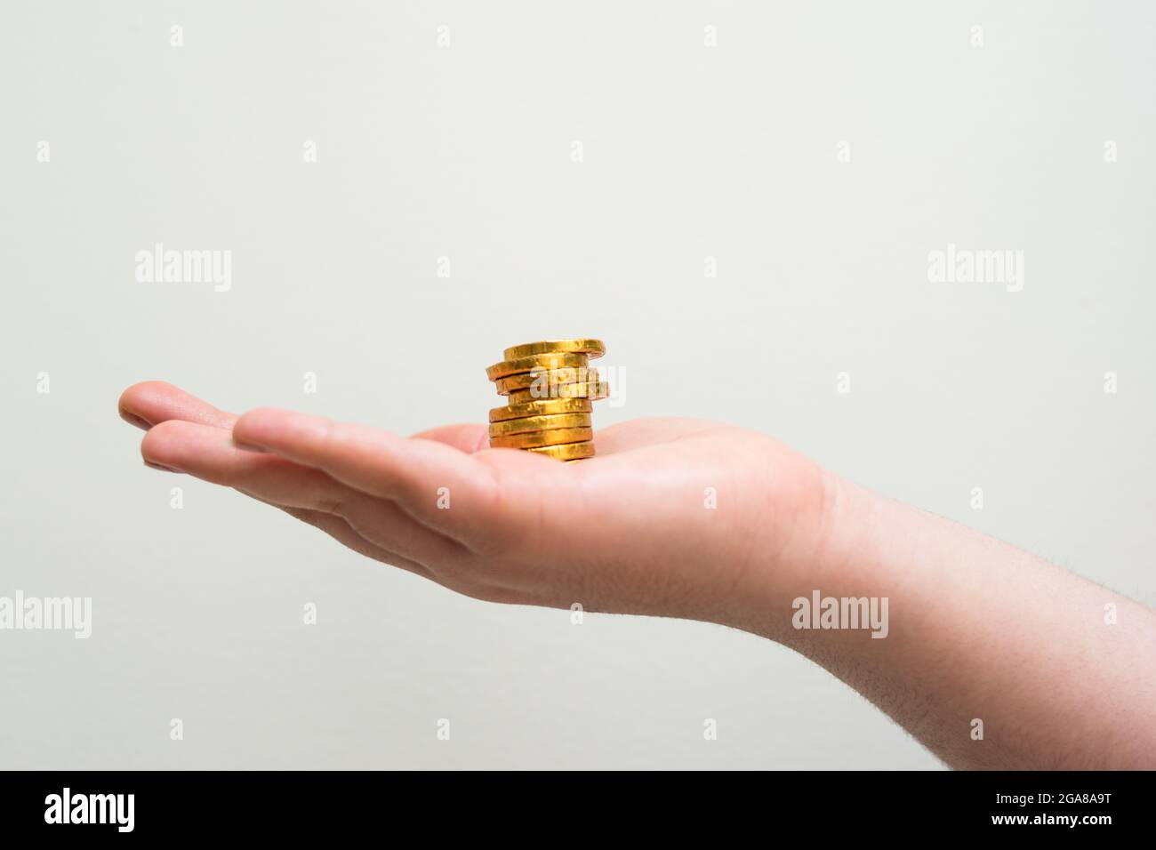 Caucasian hand holding some golden coins on a white background Stock ...