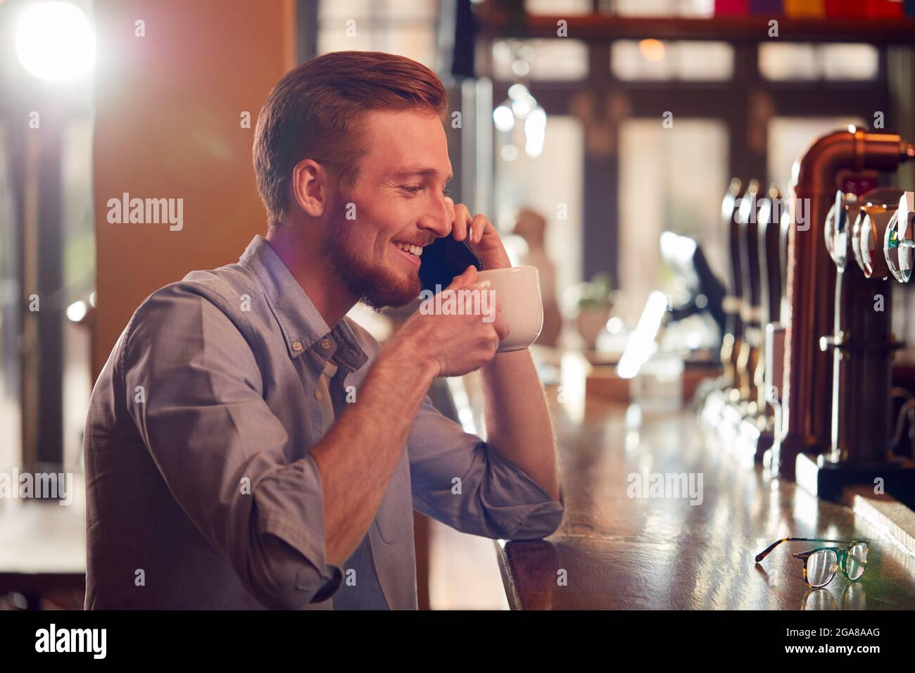 Male Owner Or Manager Of Bar Sitting At Counter Drinking Coffee And ...