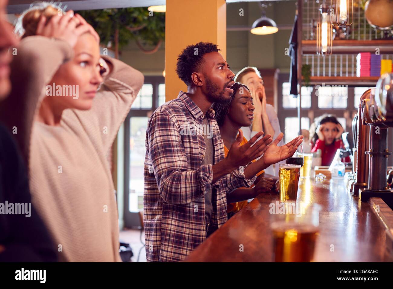 Group Of Disappointed Customers In Sports Bar Watching Sporting Event ...