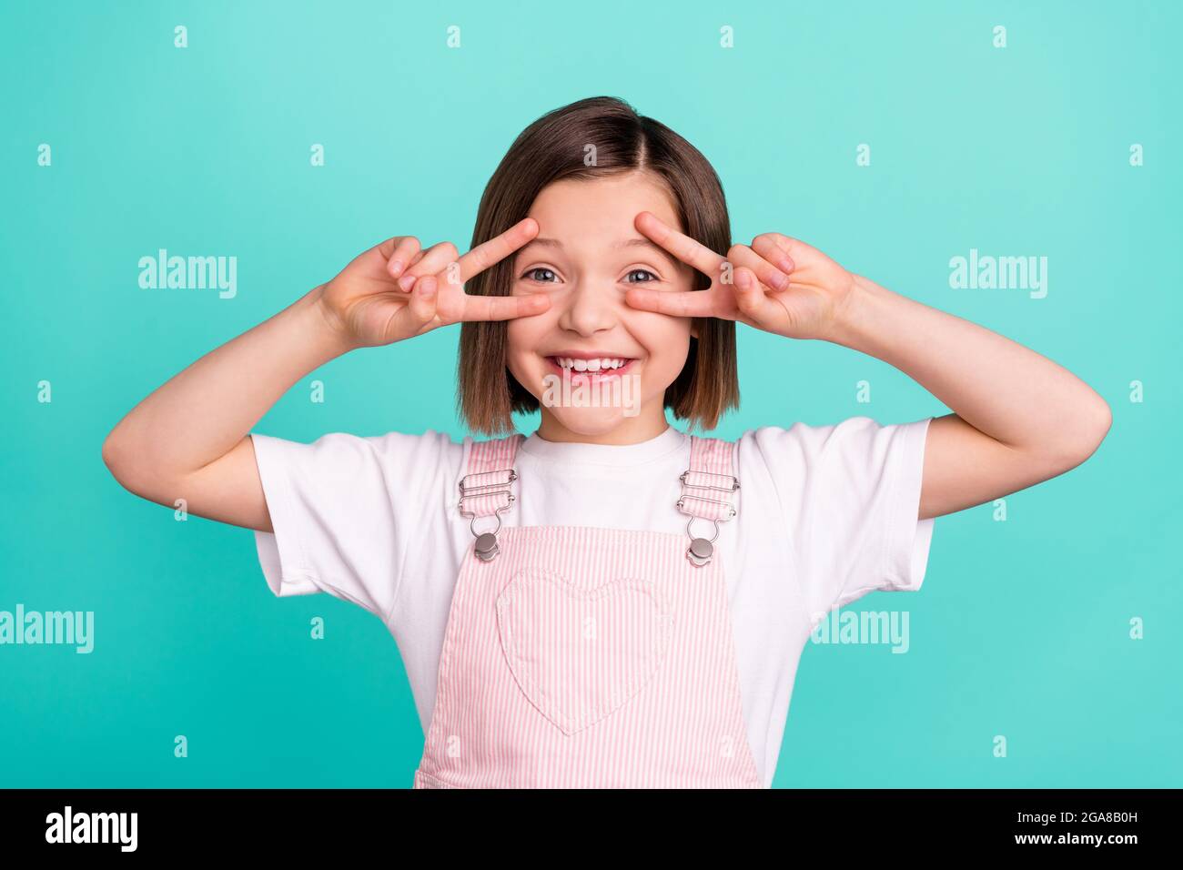 Photo of happy cheerful little girl good mood hold hands fingers face v ...