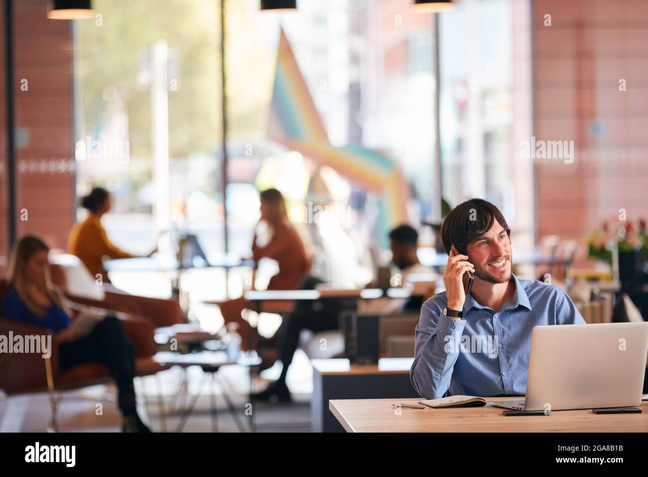 Businessman Sitting At Desk On Phone Call In Modern Open Plan Office ...