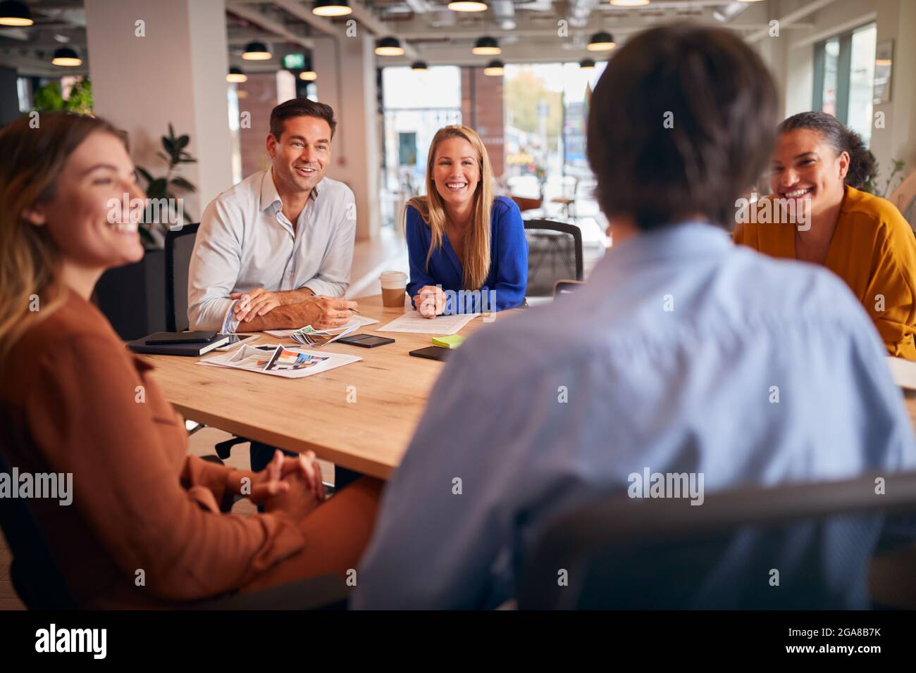 Business Team Having Meeting Sitting Around Table In Modern Open Plan ...