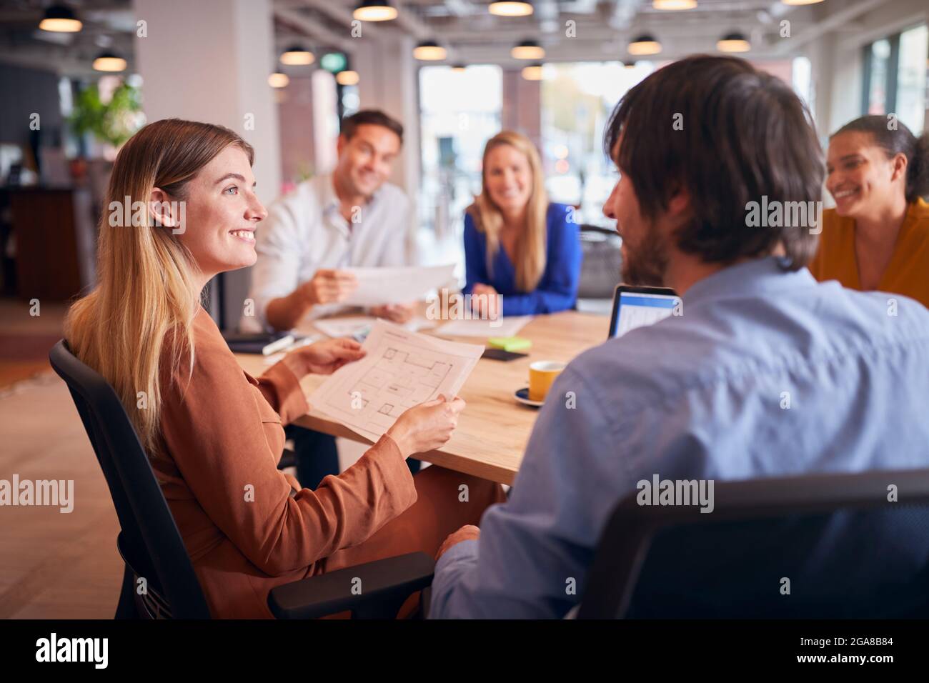Business Team Having Meeting Sitting Around Table In Modern Open Plan ...