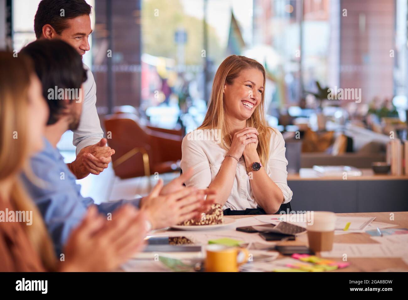 Colleagues Celebrating Businesswoman's Birthday At Meeting Around Table ...