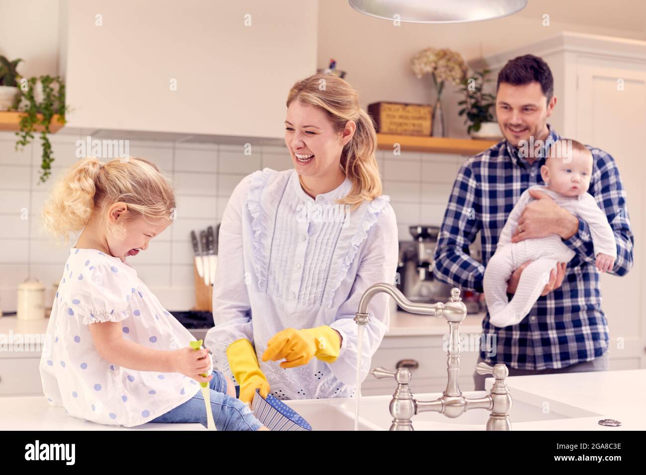 Smiling Family Having Fun In Kitchen Doing Washing Up At Sink Together ...