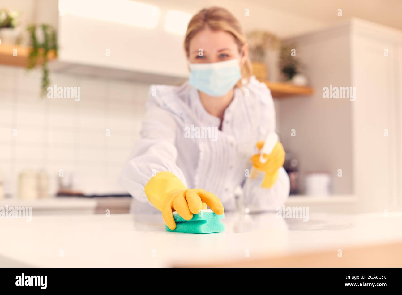 Woman At Home Wearing Mask In Kitchen Doing Housework And Cleaning ...