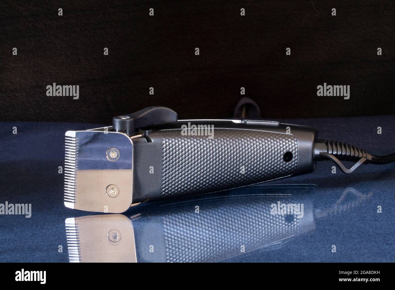 An electric razor for cutting hair is lying on a glass table. Equipment ...