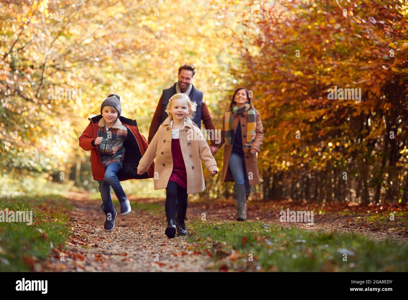 Family Walking Along Track In Autumn Countryside With Children Running ...