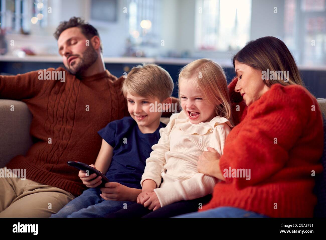 Family Sitting On Sofa Watching TV Together As Parents Fall Asleep ...
