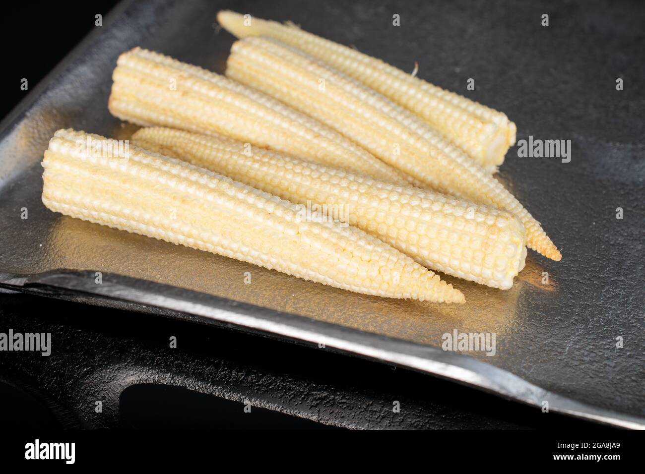 Several bright yellow ripe sweet organic mini corn on a metal tray ...