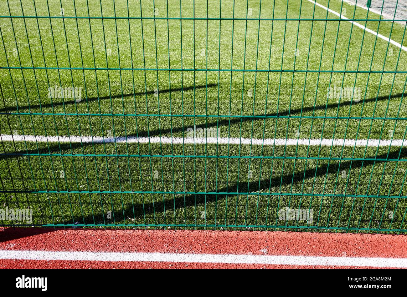 Lawn field for playing football behind the green fence mesh. Close-up ...