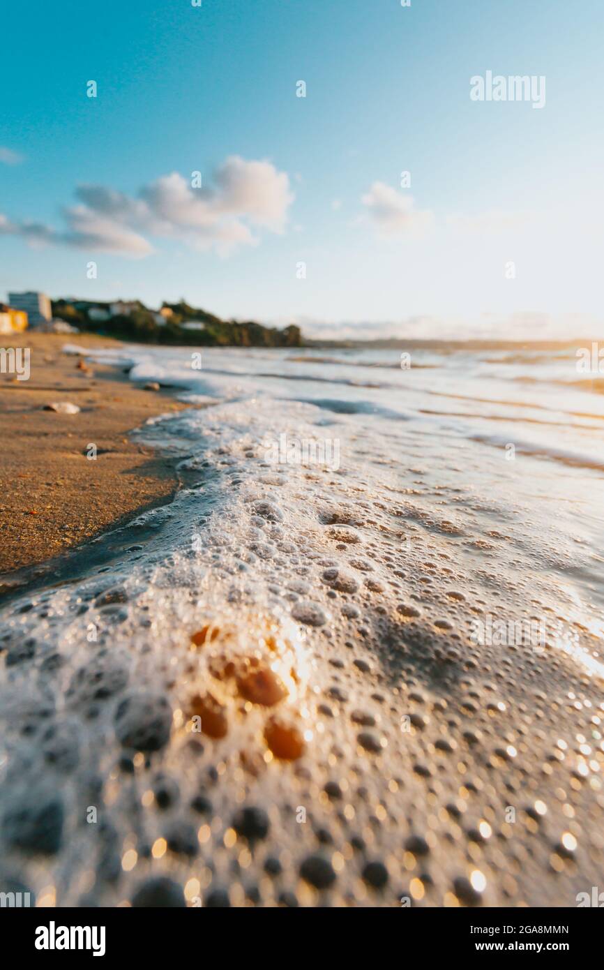 Bubbly waves of the ocean on the sand beach at golden sunset Stock ...