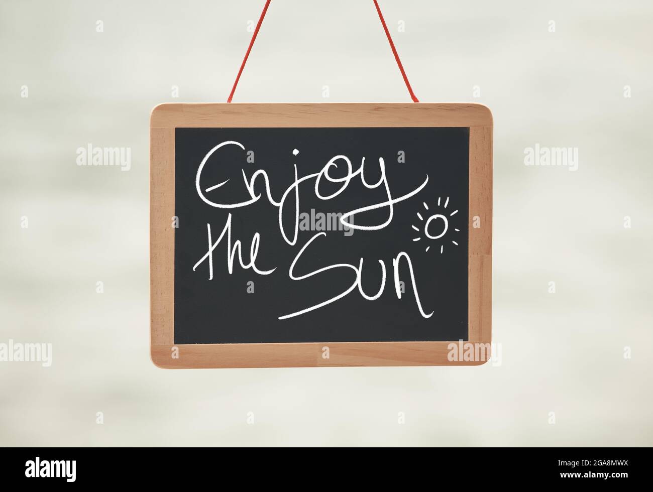 Wooden framed small blackboard with a "Enjoy the Sun" writing hanging ...