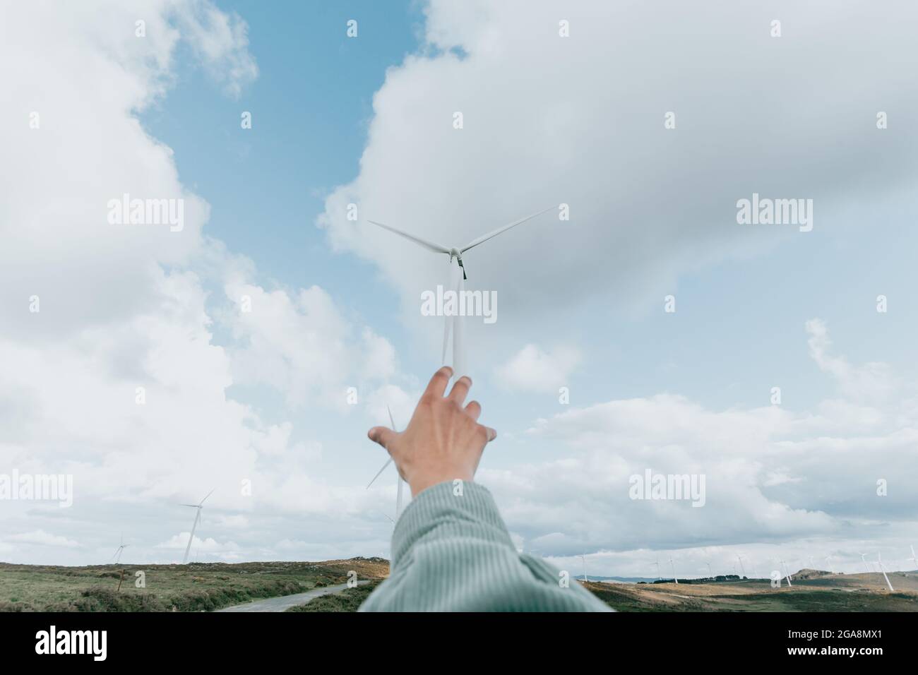 Human hand reaching wind turbines in the field on a cloudy day Stock ...