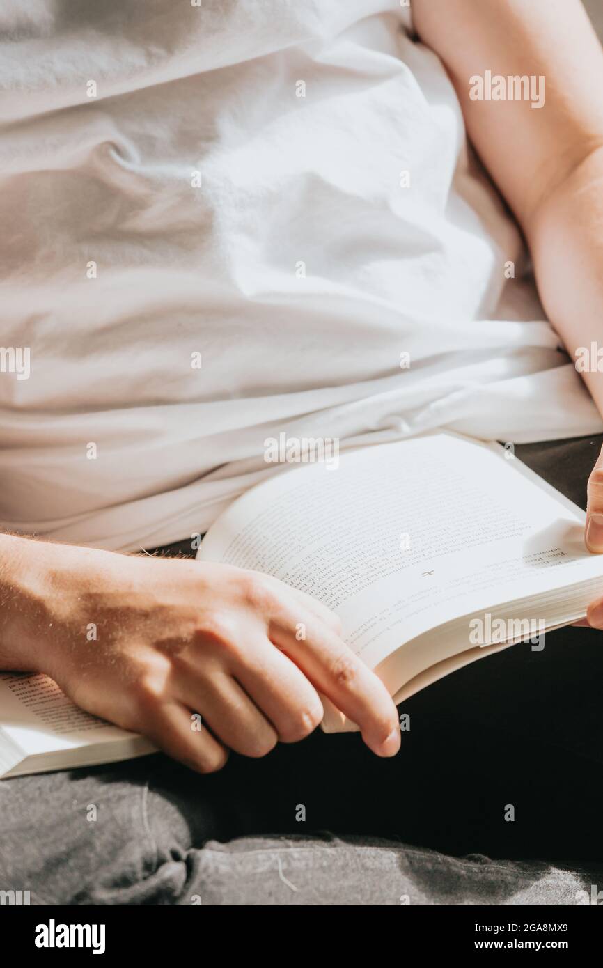 Closeup of hands grabbing and reading a book in sunlight, relaxing ...