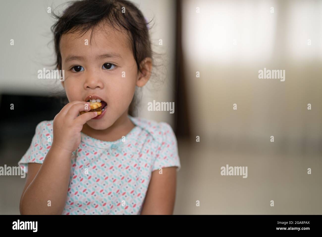 Cute Asian female child eating a cookie Stock Photo - Alamy