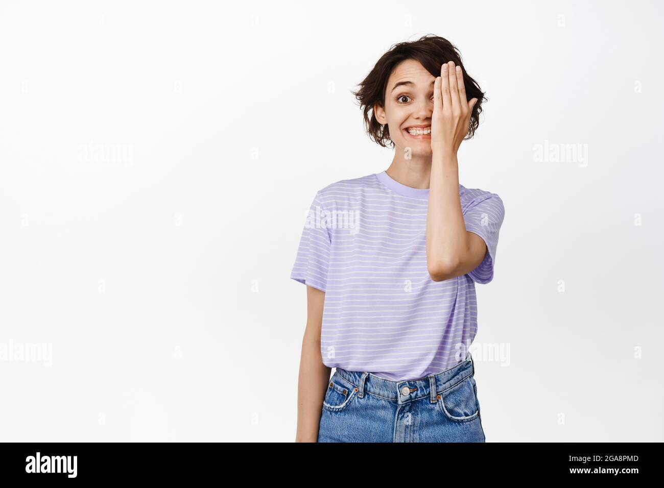 Happy beautiful girl hide one side of face, looking at camera excited ...