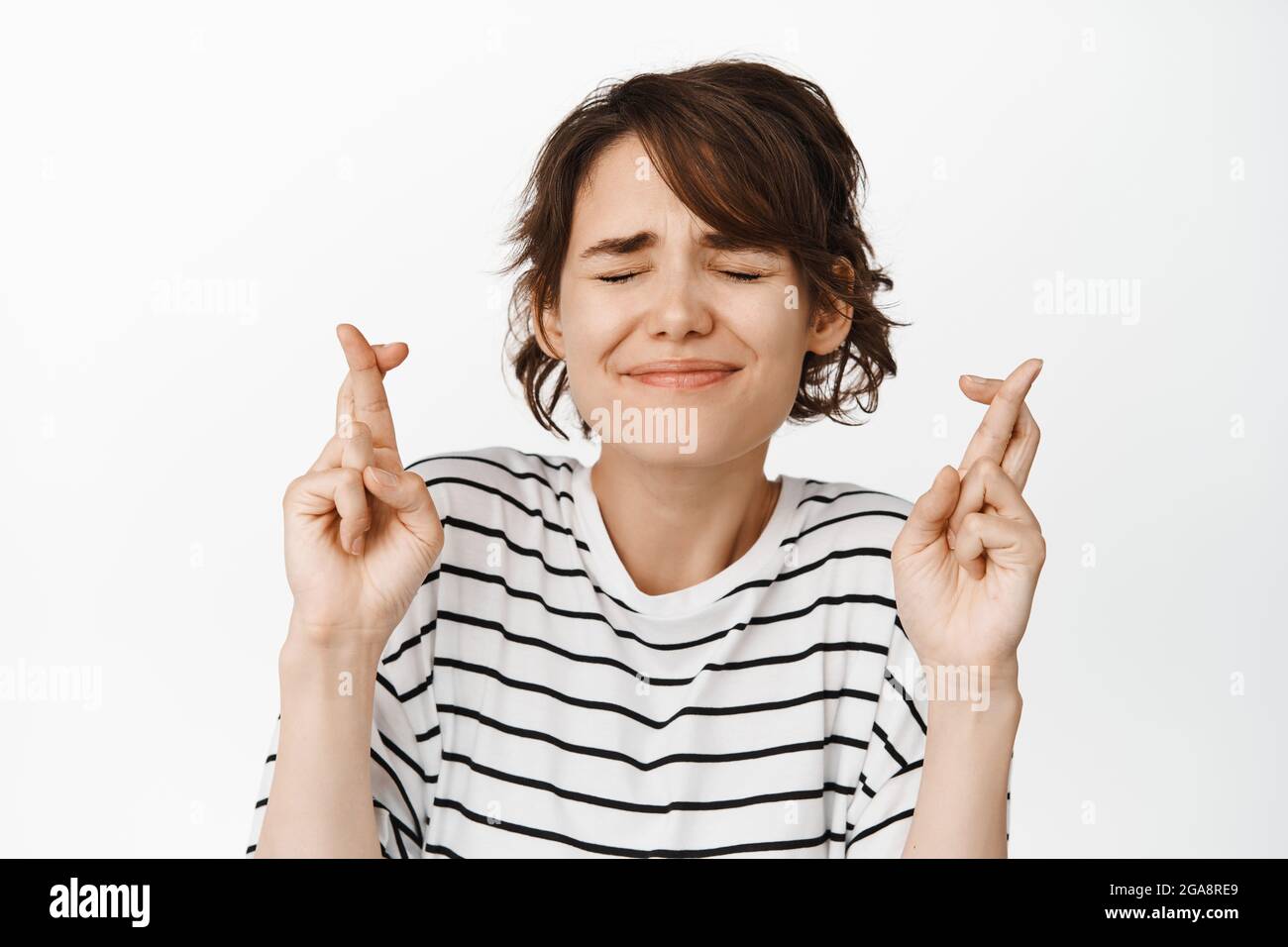 Close up portrait of hopeful nervous girl close eyes, smiling with ...