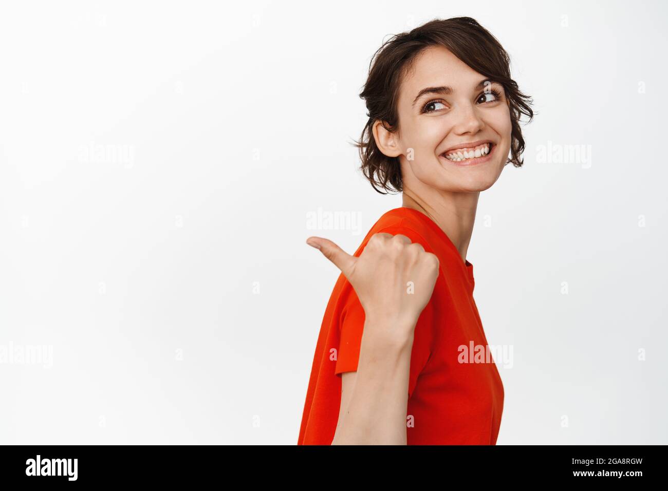 Image of smiling brunette woman pointing finger left, looking behind ...