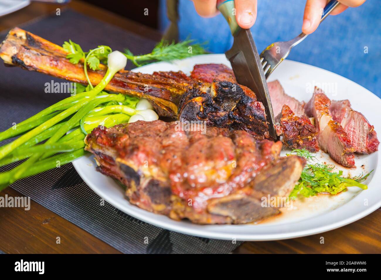 A man cuts cooked fried meat in a plate. Oven-roasted meat for dinner ...