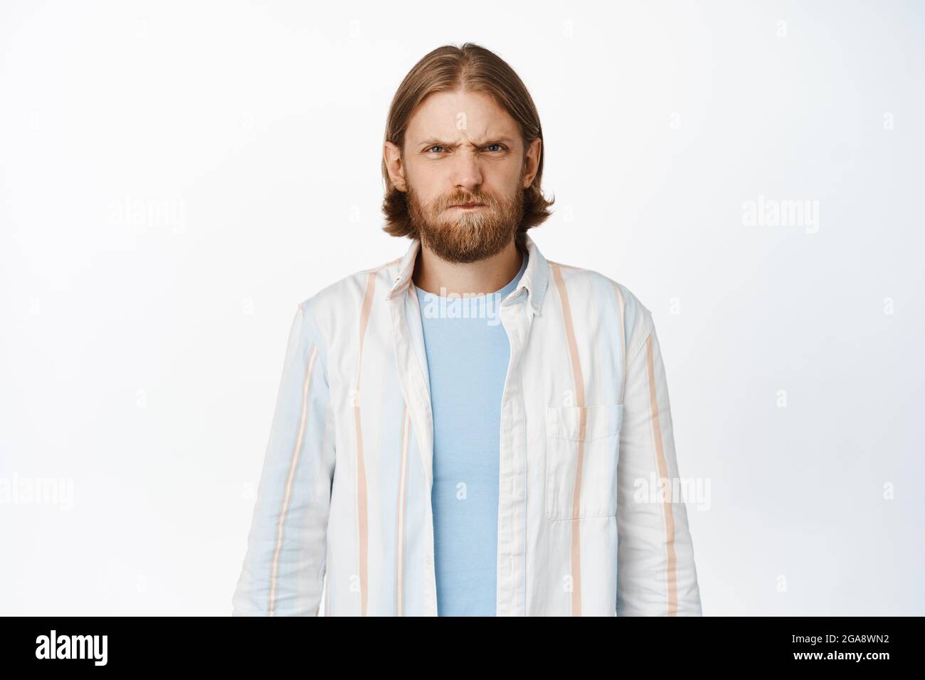 Despise. Angry and grumy blond guy sulking, furrow eyebrows and staring ...