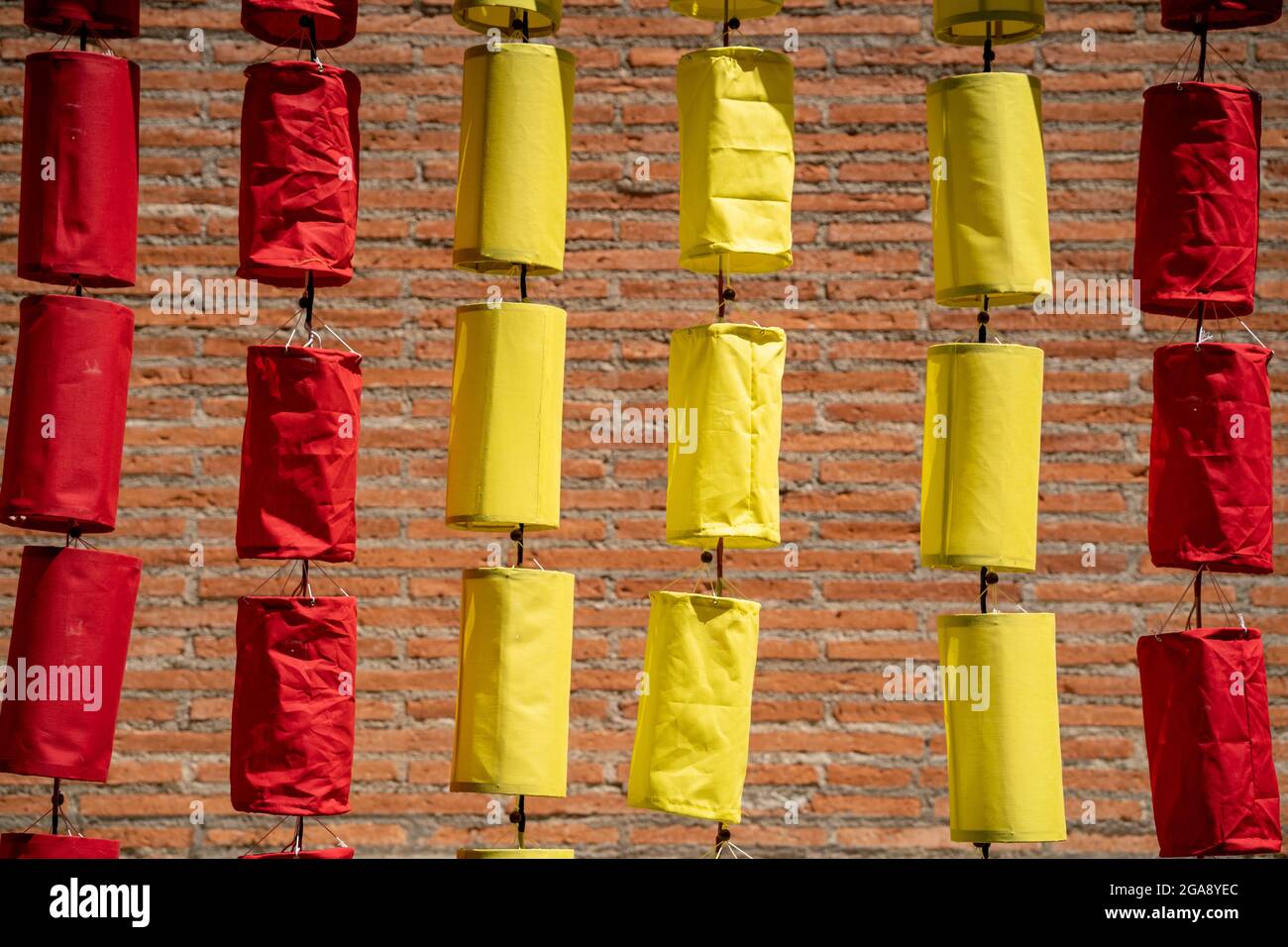 Hanging red yellow tube decorations on a brick wall background Stock ...