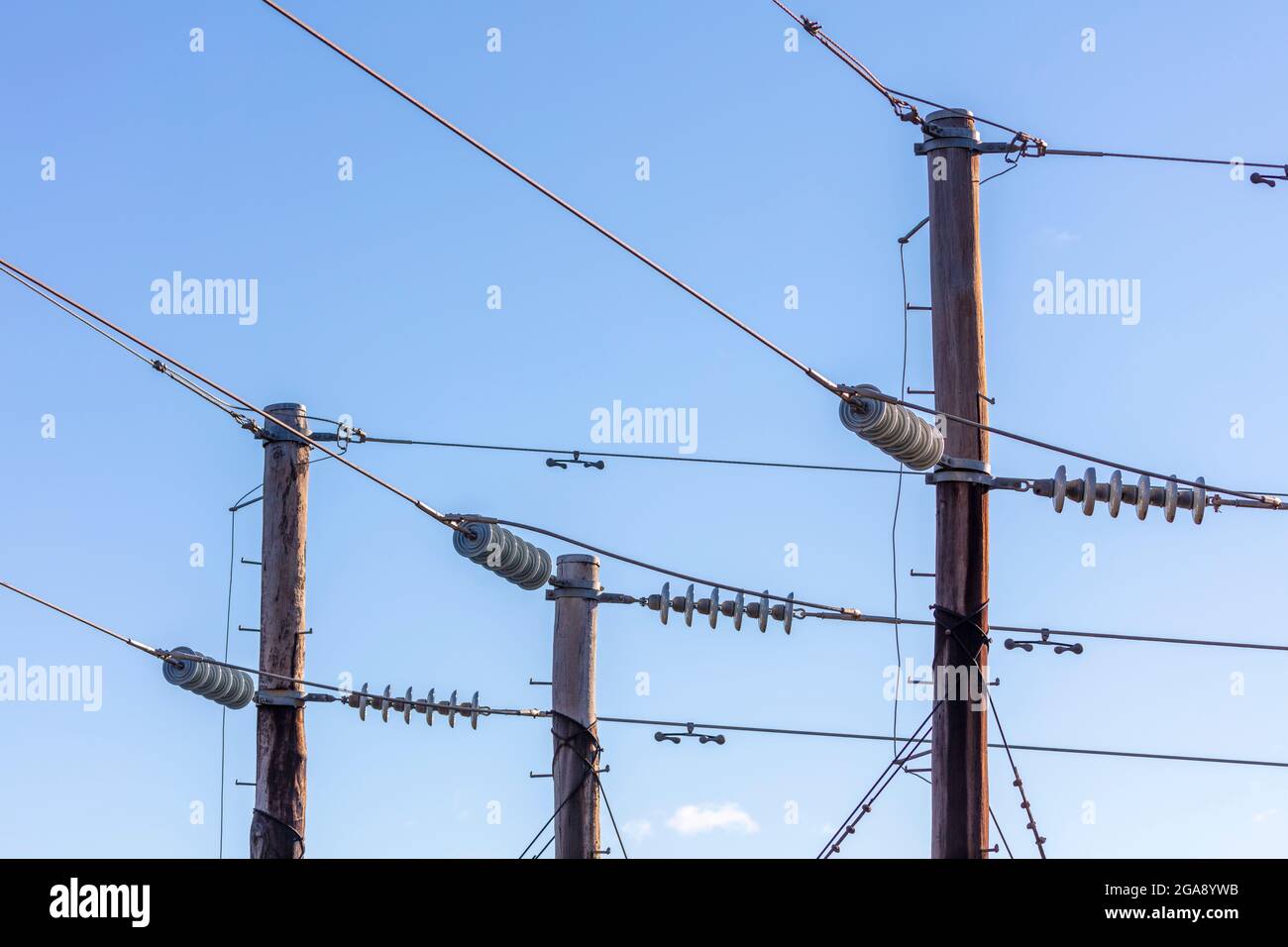 Photograph of a wooden telephone post and cables against a blue sky ...